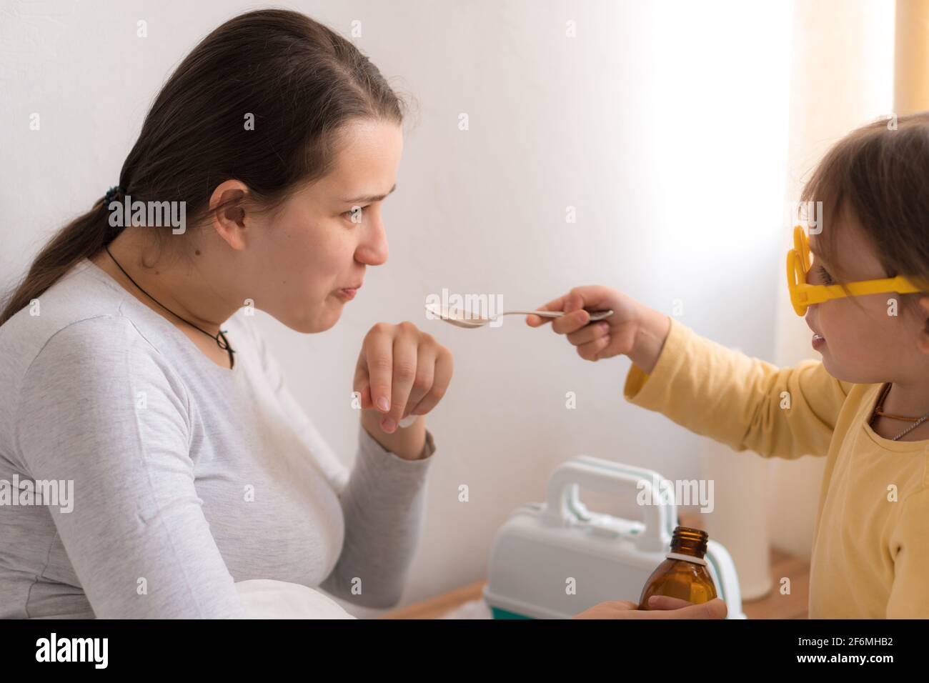 Cute little girl wearing uniform playing doctor or nurse with sick mum ...