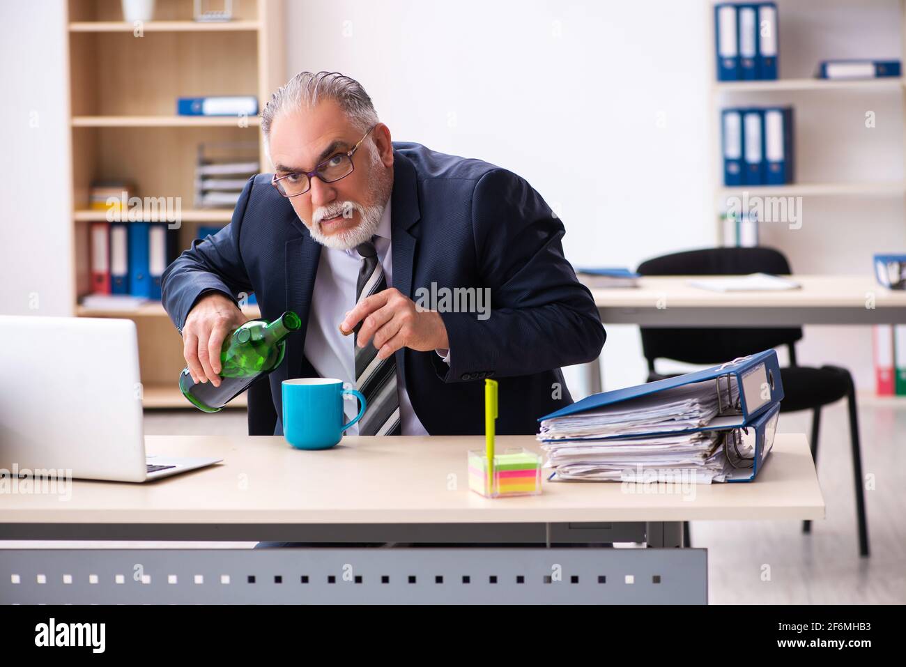 Old businessman drinking alcohol in the office Stock Photo - Alamy