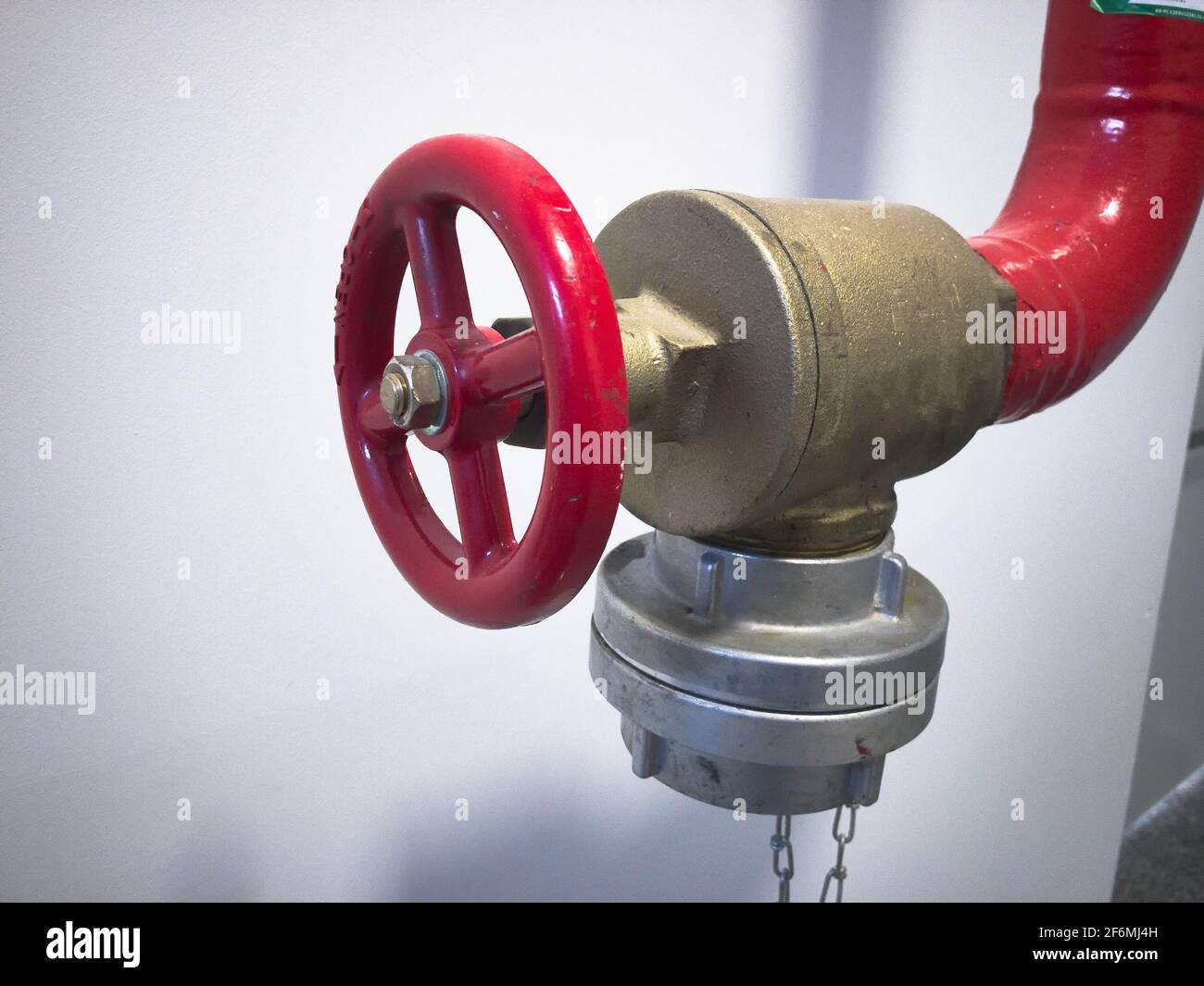 Red fire hose valve opposite white wall Stock Photo - Alamy