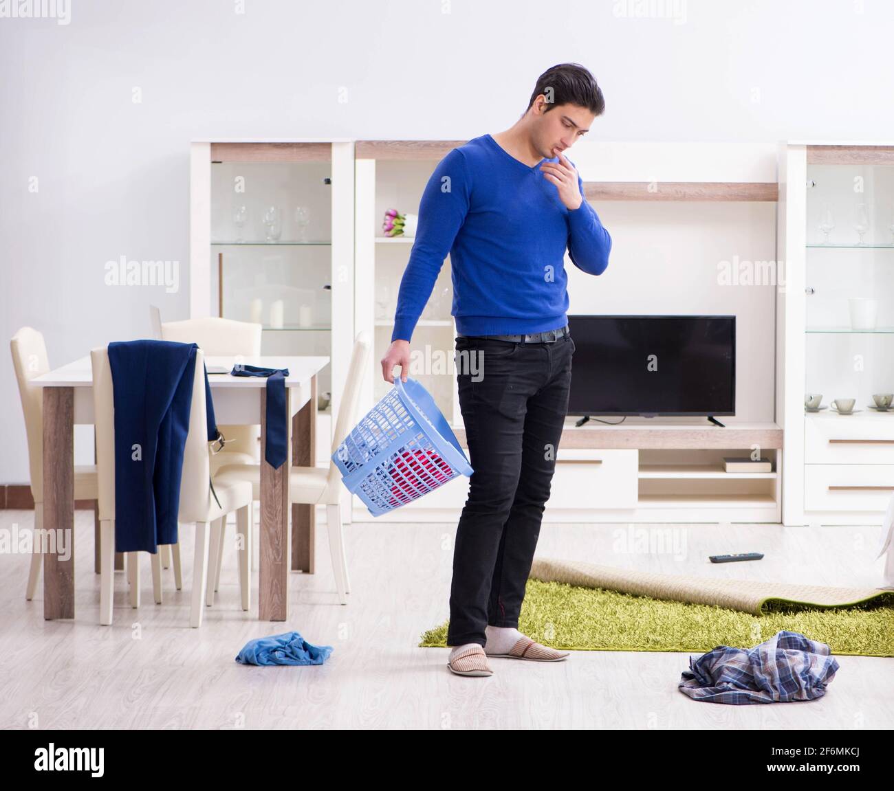 The young man collecting dirty clothing for laundry Stock Photo - Alamy