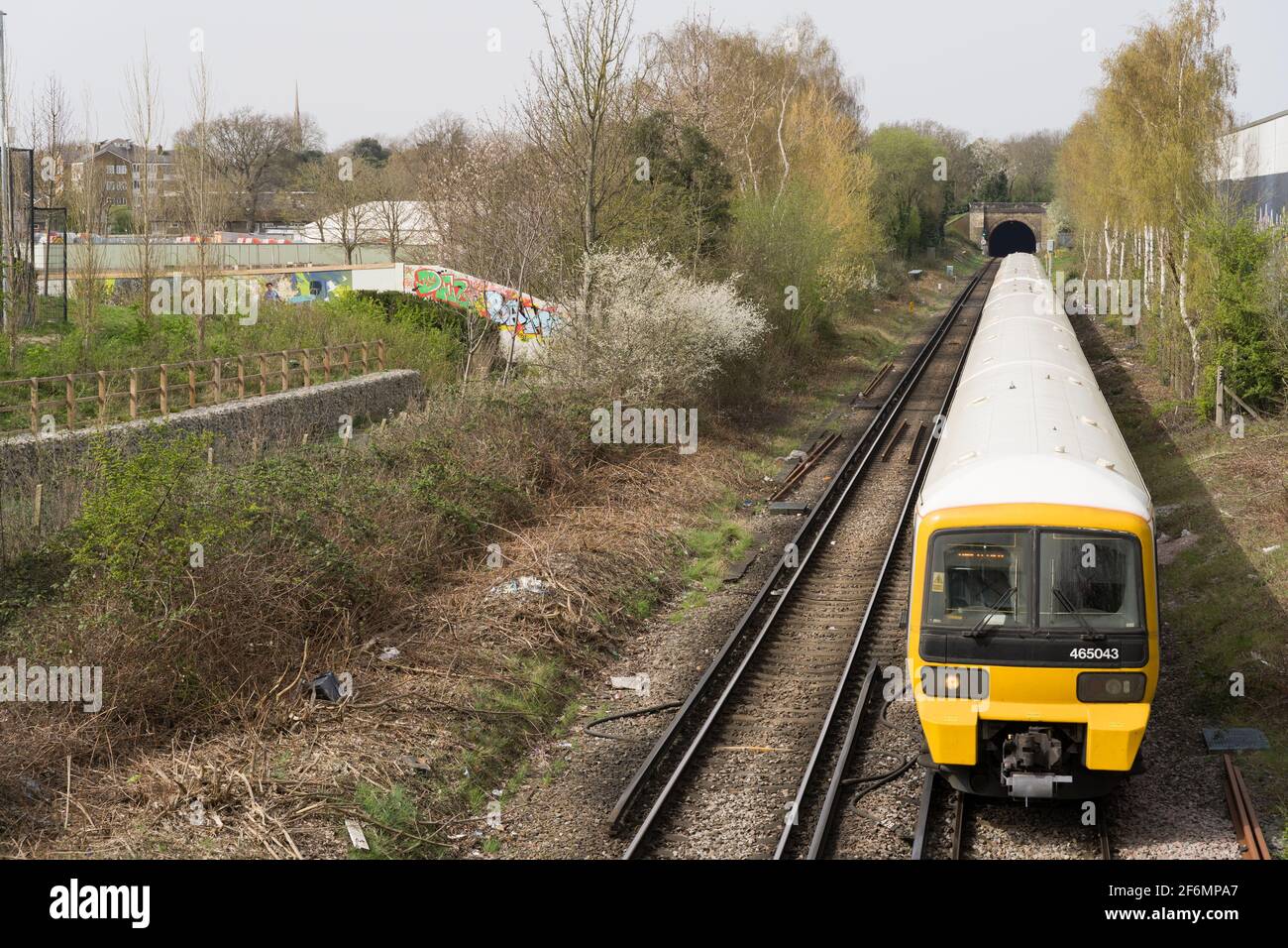 south-eastern railway train travelling out of tunnel into open flanked ...