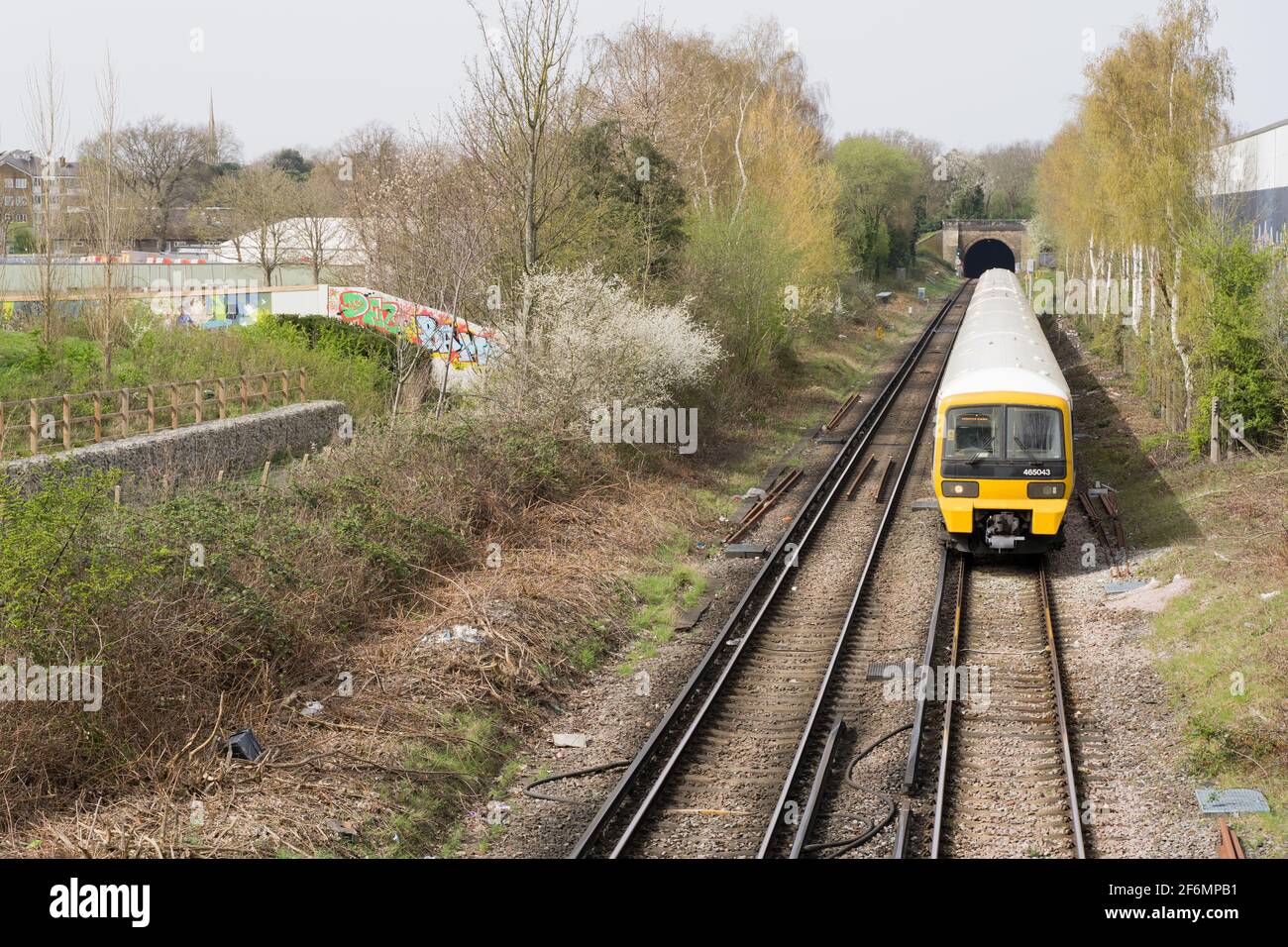 south-eastern railway train travelling out of tunnel into open flanked ...