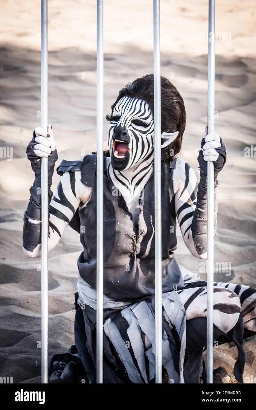 A human zebra woman crouches down behind cage bars Stock Photo - Alamy