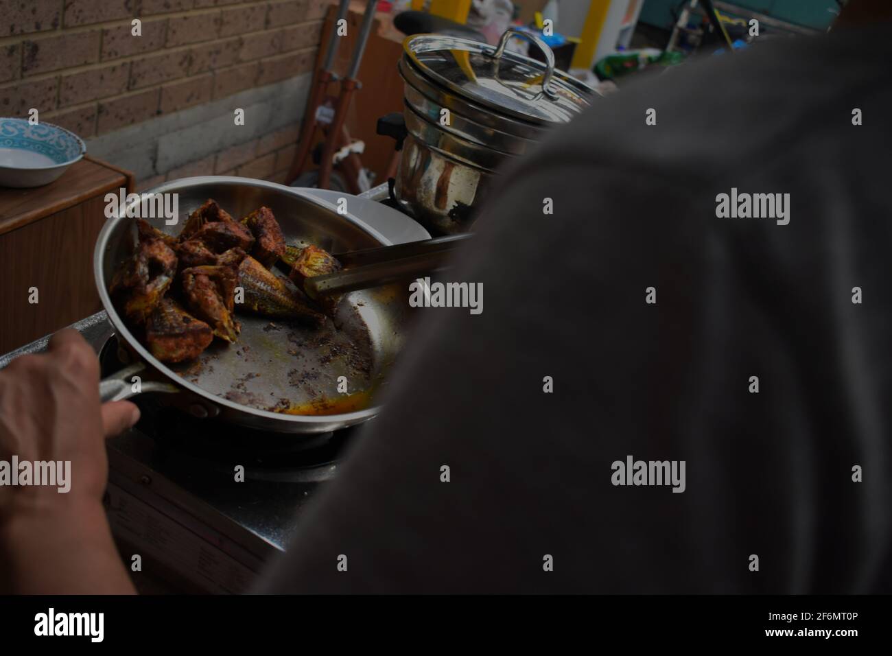 Person frying fish in a pan and separating the fish hi-res stock ...