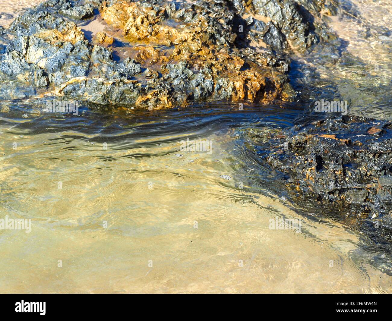 Sea water rippling in around the rocks in the rock pool on the shore ...