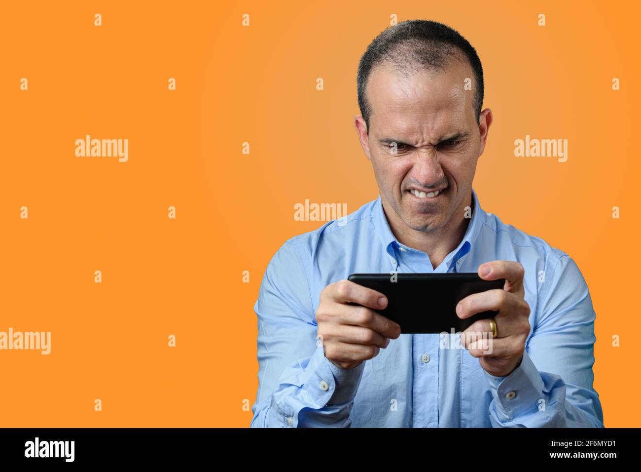 Mature man in formal wear playing on his smartphone and biting his ...