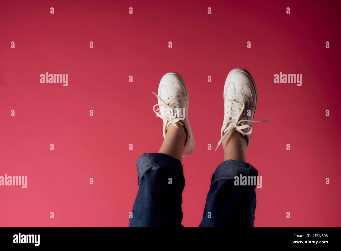 Inverted female legs white sneakers motion street style pink background ...