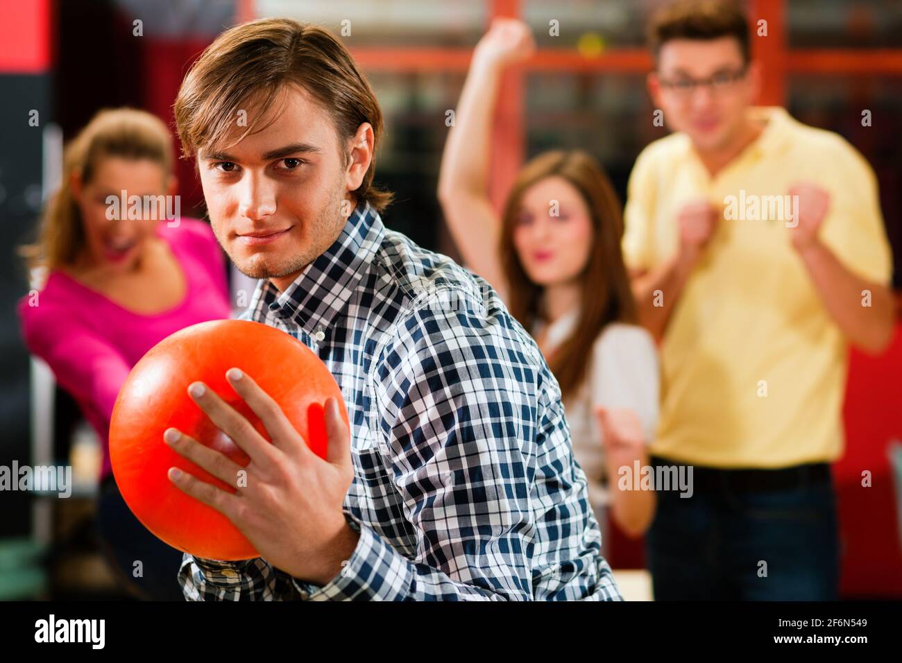 Group of four friends in a bowling alley having fun, three of them ...