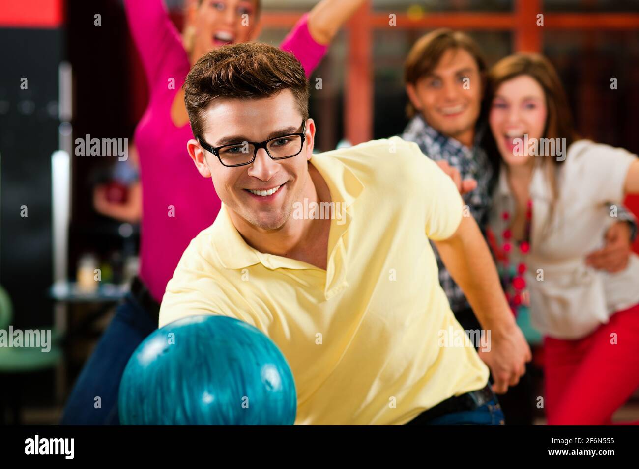 Group of four friends in a bowling alley having fun, three of them ...