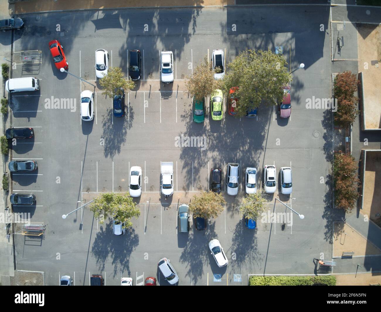 Cars parked aerial view in a carpark, with buildings and greenery ...