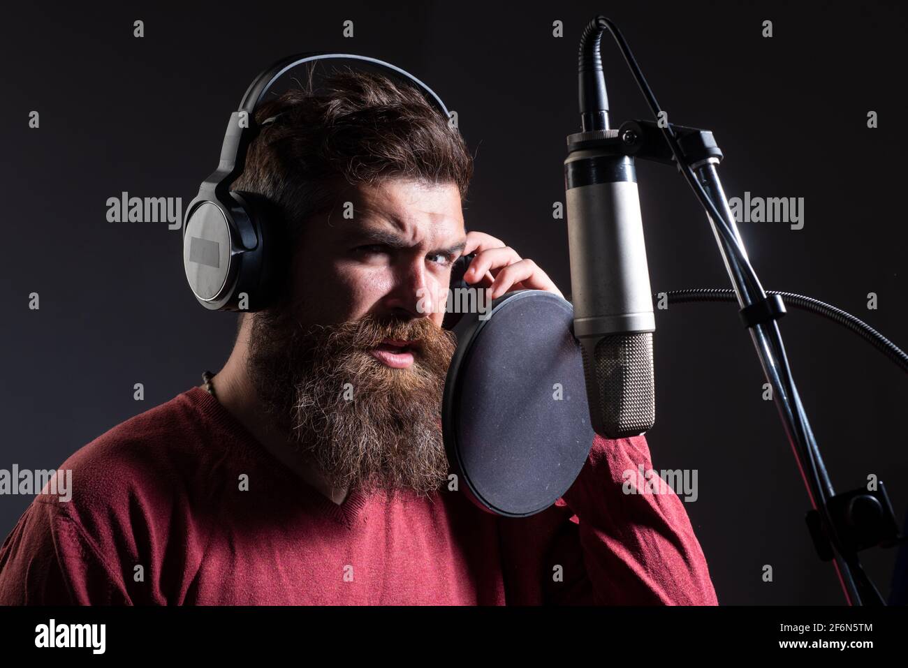 Portrait of singer wearing headphones is performing a song with a ...