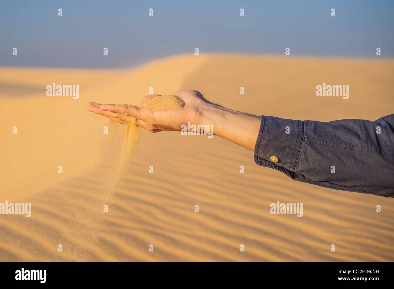 Desert, sand puffs through the fingers of a mans hand Stock Photo - Alamy