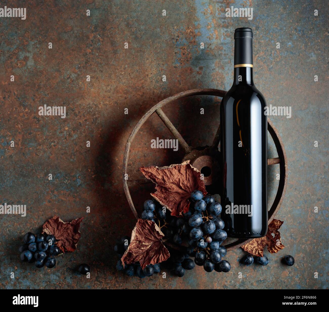 Bottle of red wine with an old rusty wheel. Top view with copy space ...