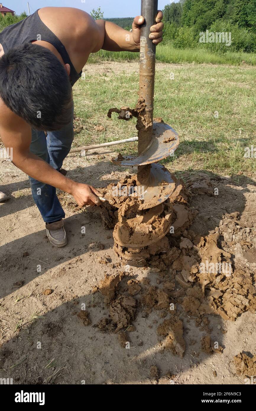 Workers are drilling pits for poles, starting work with a hand drill ...