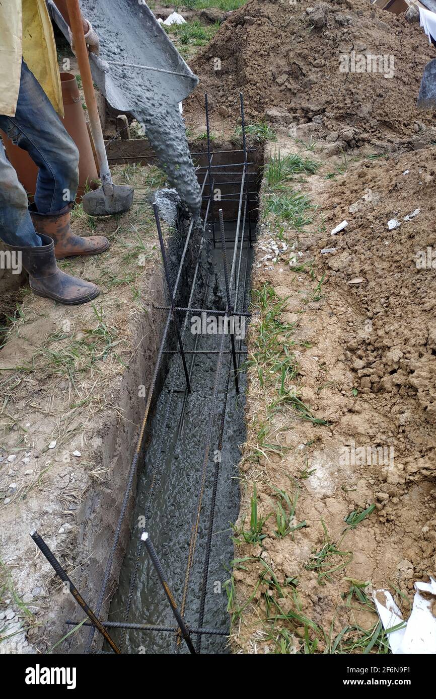 pouring cement into the trench with a mixer, construction work in the ...