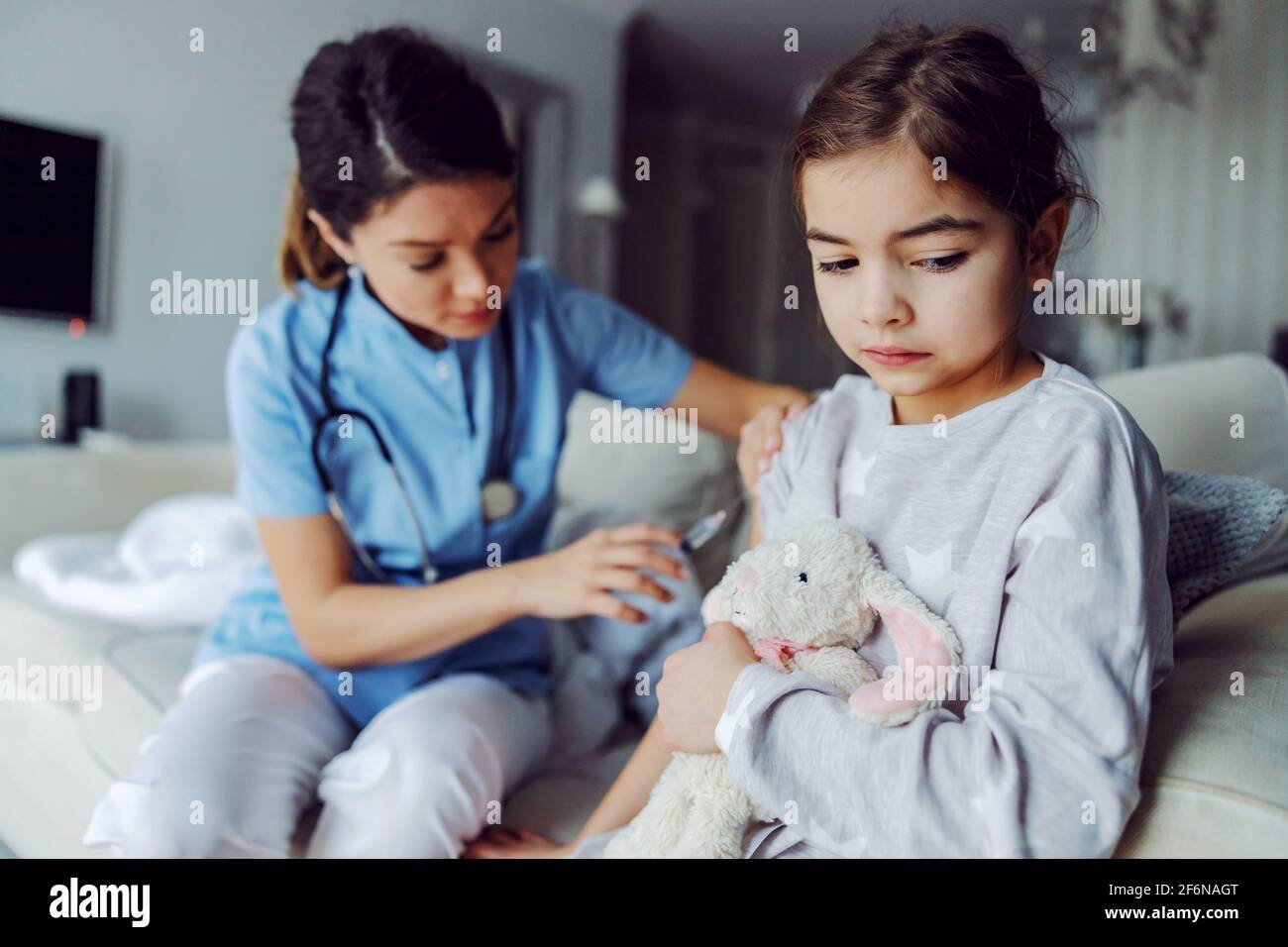 Scared little girl sitting on sofa and getting vaccine Stock Photo - Alamy