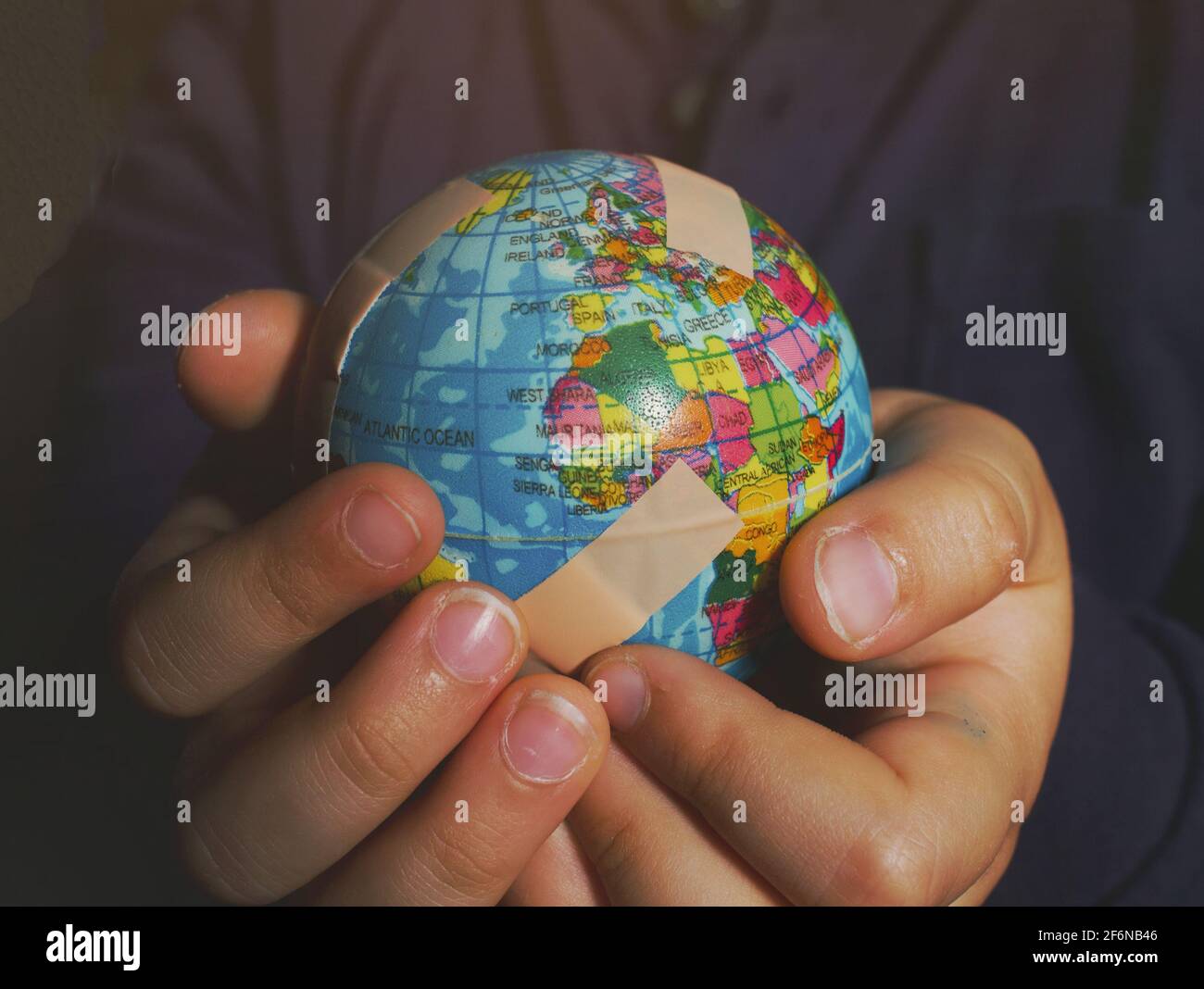 Natural Hands of a boy holding a Globe full of bandages. Global warming ...