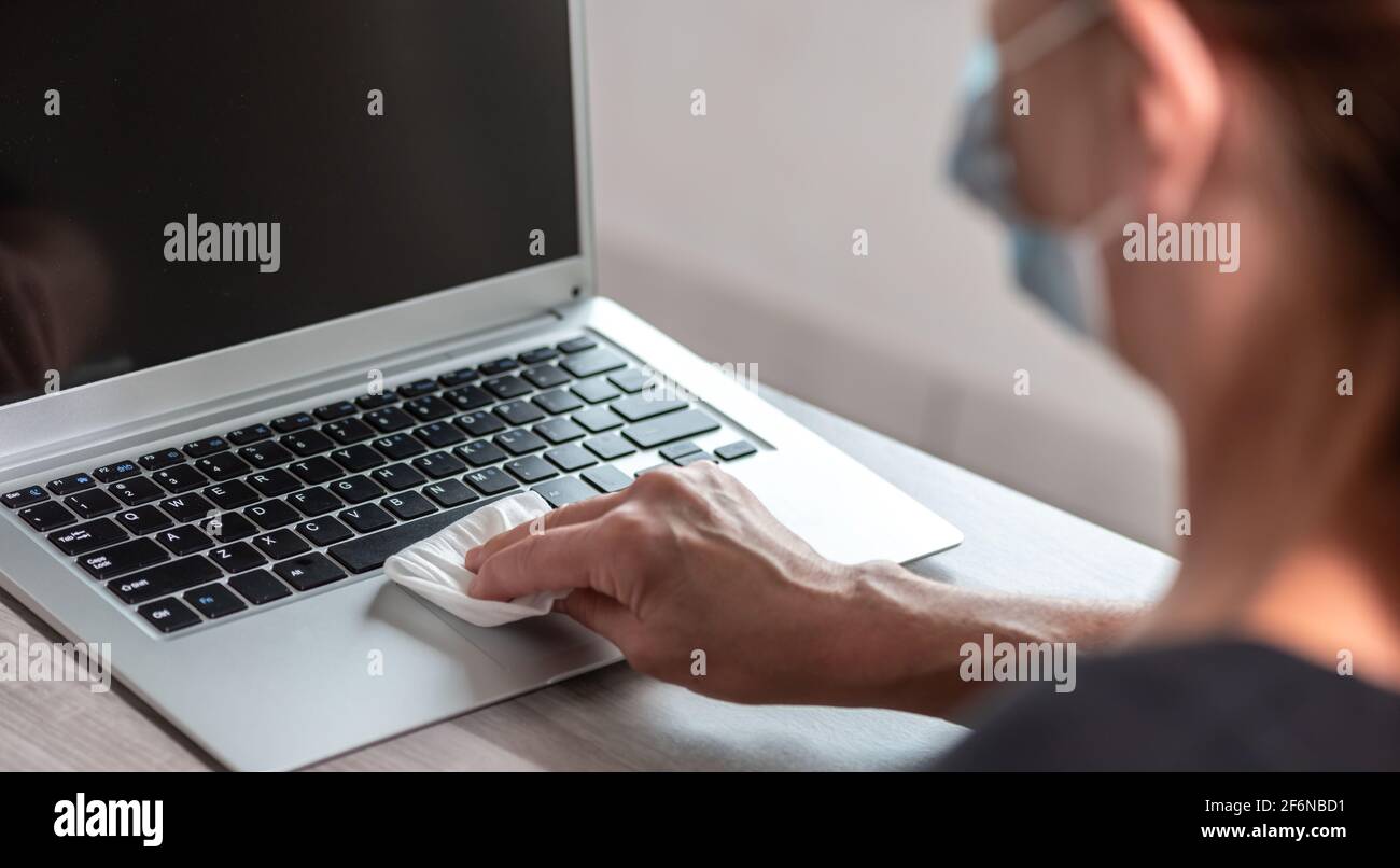 Woman disinfecting laptop keyboard with antibacterial wipe; prevention ...