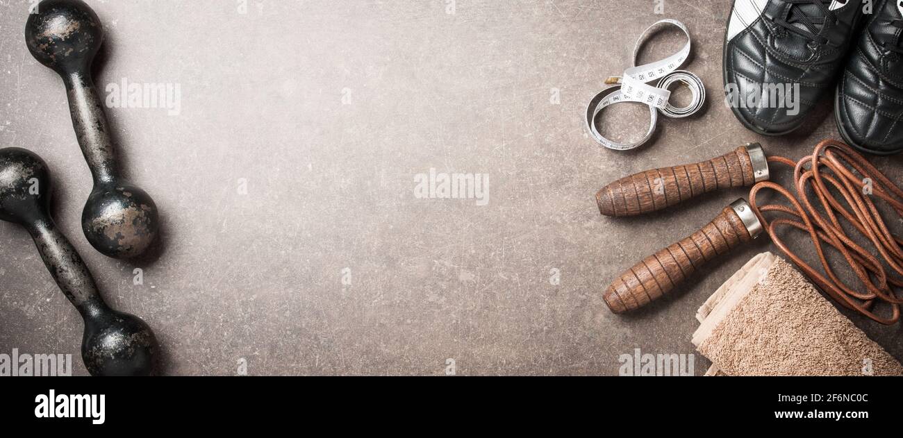 Fitness background with dumbbells, skipping rope, sneakers and towel ...