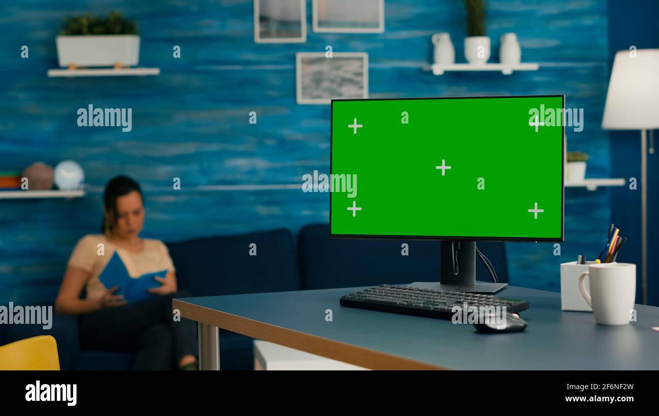 Woman lying on sofa reading a book in living room equipped with desktop ...