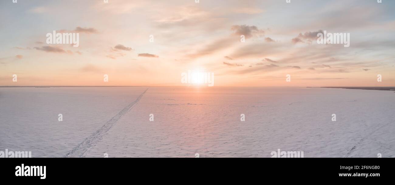 Ice on the frozen sea and bright colored sky at sunset. Aerial long ...