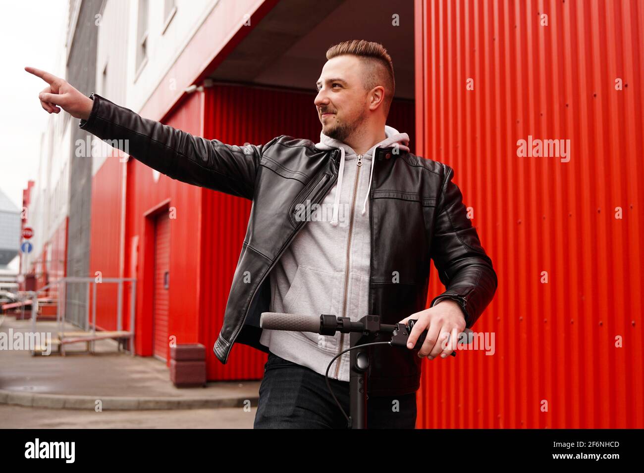 Young attractive man on electric scooter over red background Stock ...