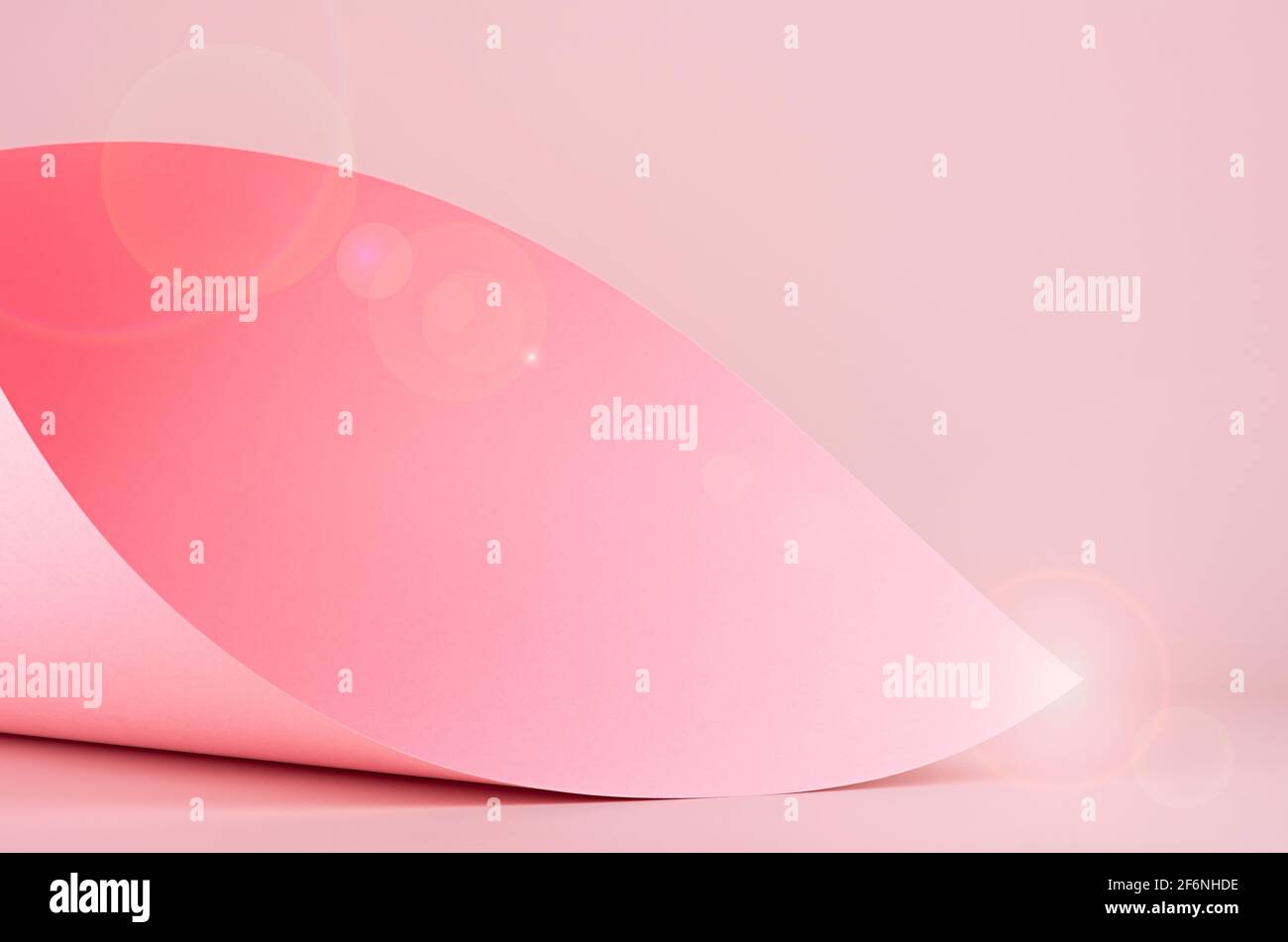 Pink paper folded as roll with sun flares and sun beam, corner as ...