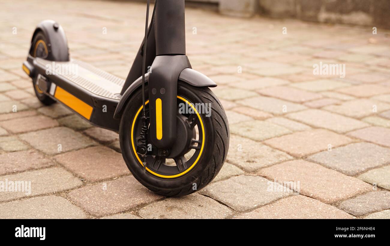 A close-up of the front wheel of an electric scooter against a tile ...