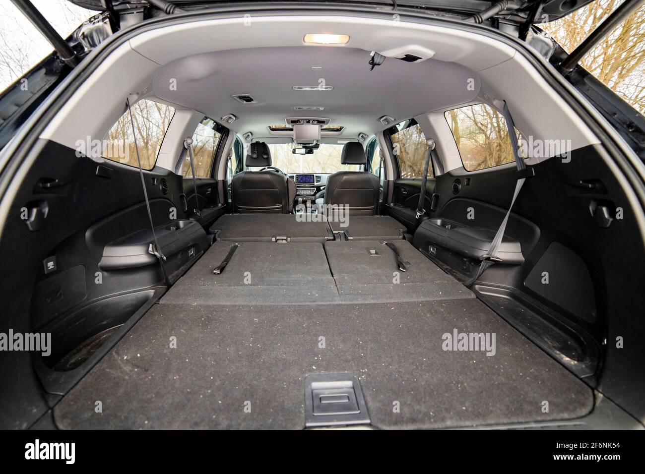 rear view open car trunk with folded passenger seats.. large empty flat ...