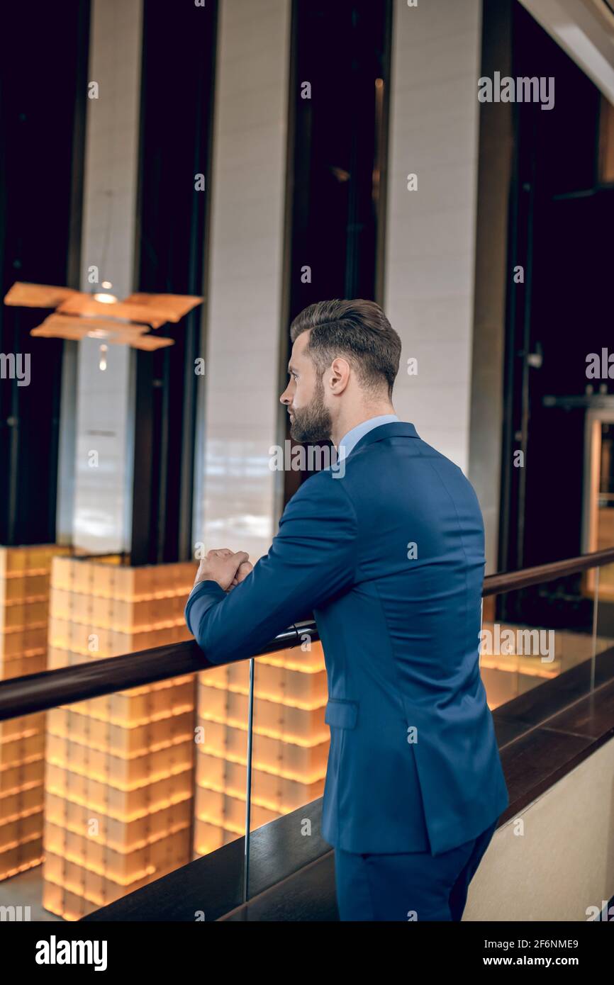 In thoughts. Elegant businessman standing and looking concentrated ...