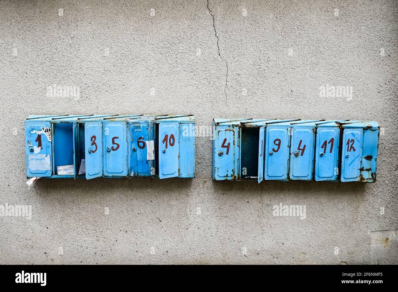 Old rusty mailboxes on the wall. Blue broken mailboxes with numbers ...
