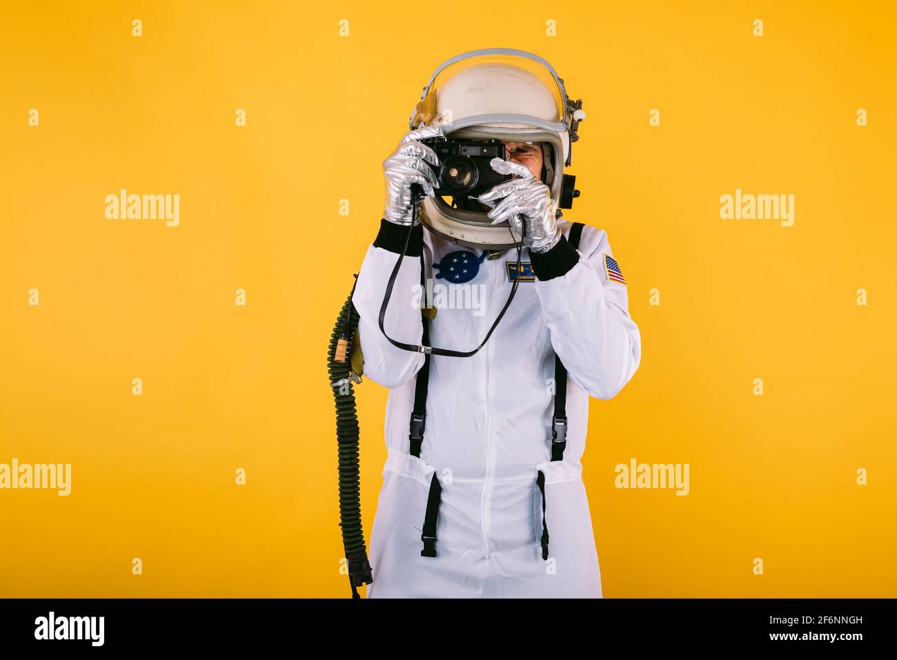 Male cosmonaut in space suit and helmet, taking a picture with a retro ...
