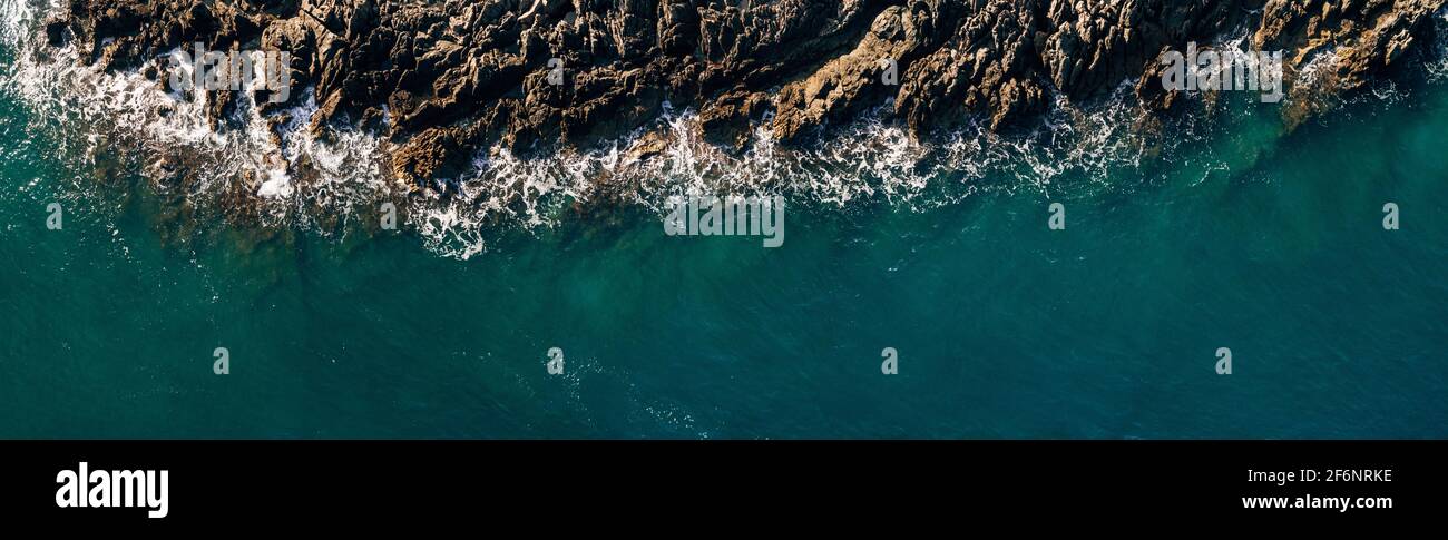 The ocean's wave hitting rocks. Blue water background. Aerial view. The ...
