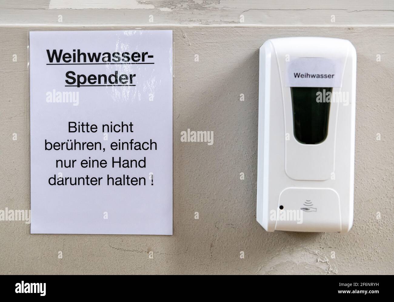 02 April 2021, Bavaria, Munich: An automatic holy water dispenser hangs ...