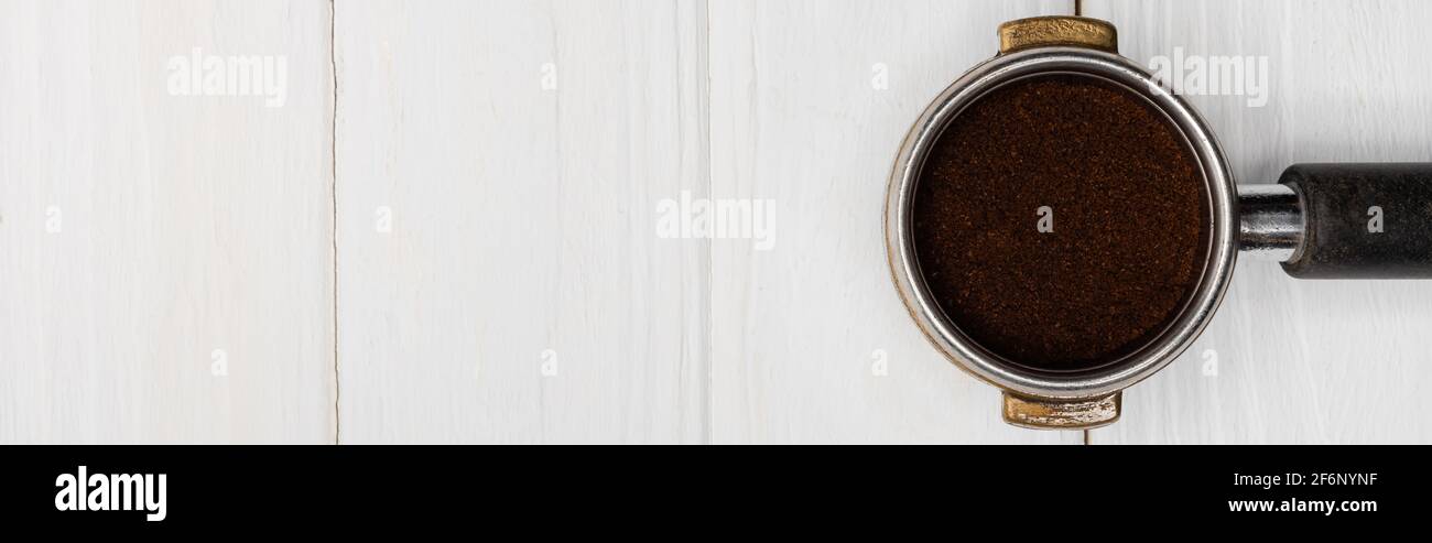 top view of metallic portafilter with fresh ground coffee on white ...