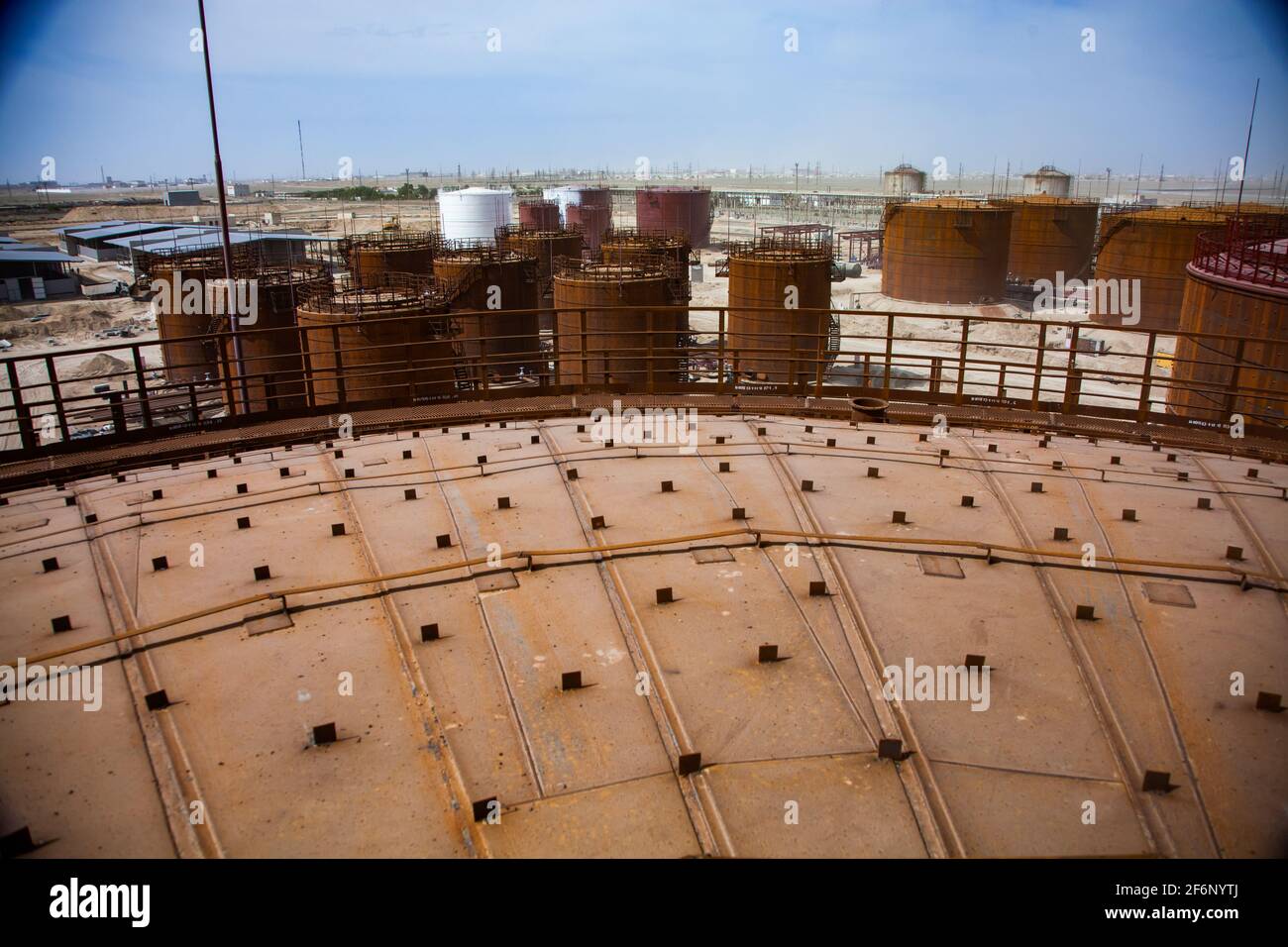 Rusted oil storage tanks on blue sky background. View from tank's roof ...