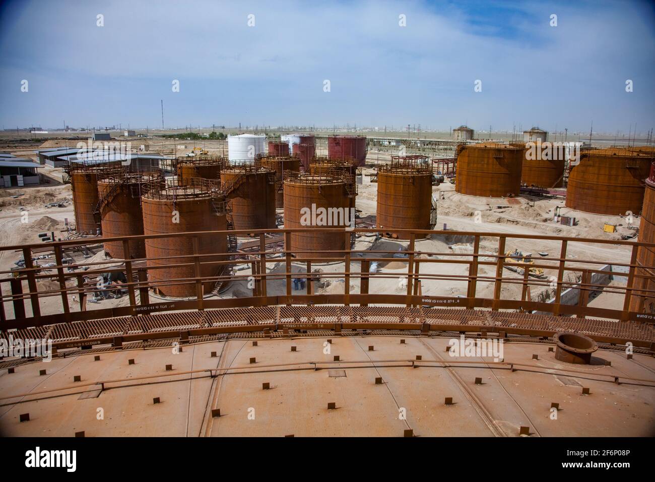 Rusted oil storage tanks on blue sky background. View from tank's roof ...