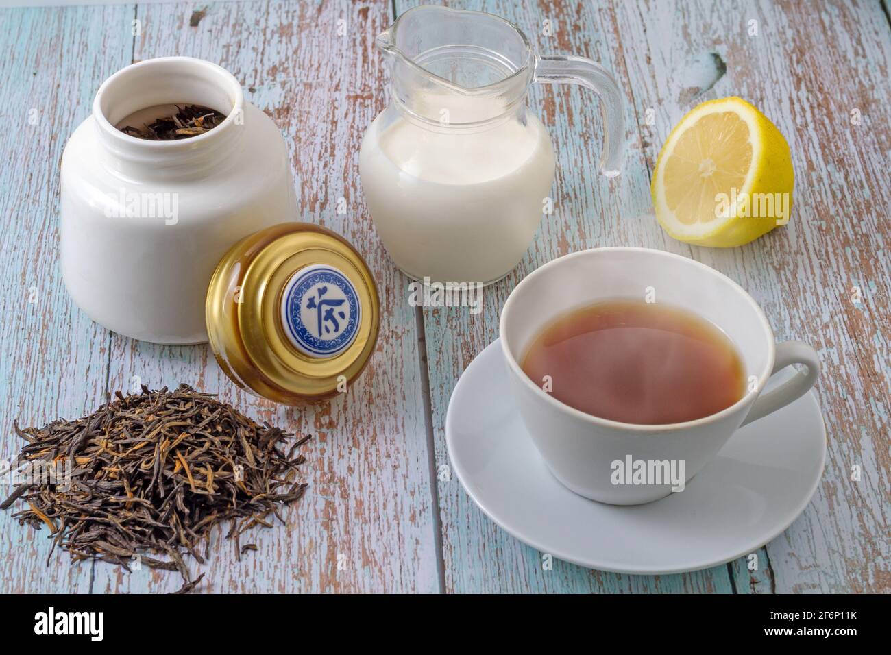 Tea leaves ready for infusion, white cup with tea infusion, lemon cut ...