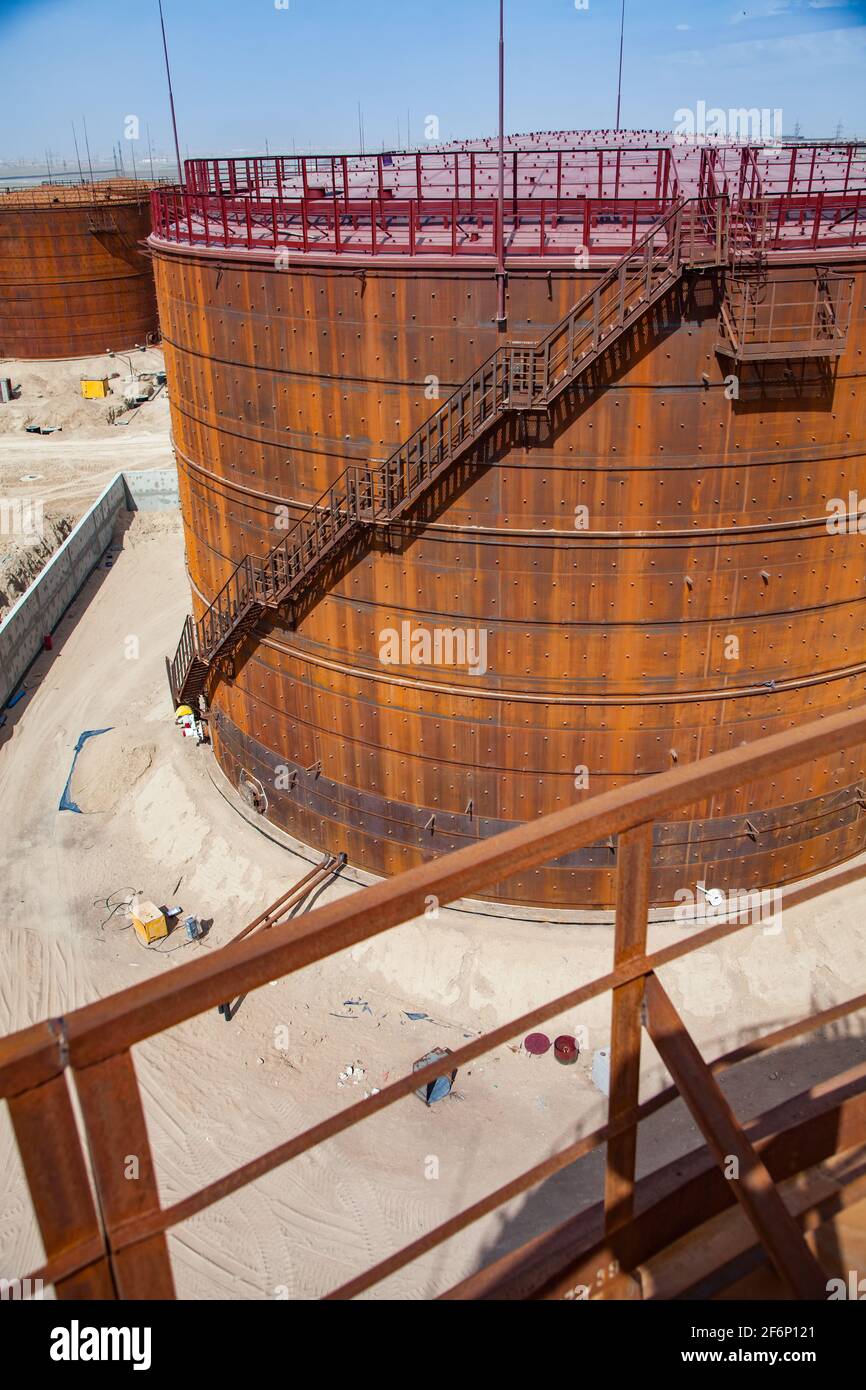 Rusted oil storage tanks on blue sky background. View from tank's roof ...