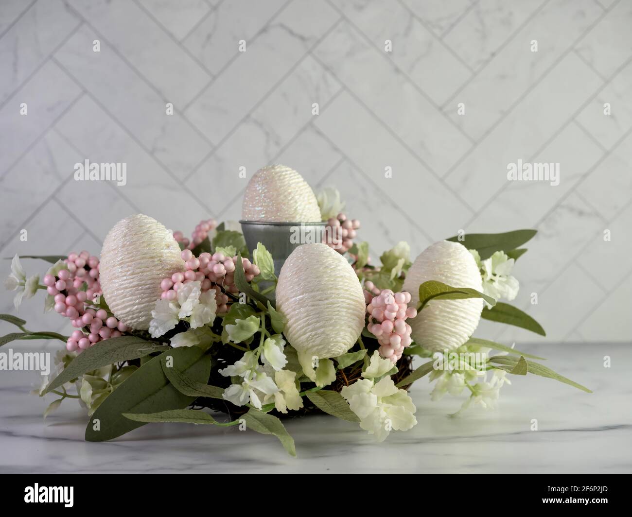 Pink floral wreath with white Easter eggs decorated with string sitting ...