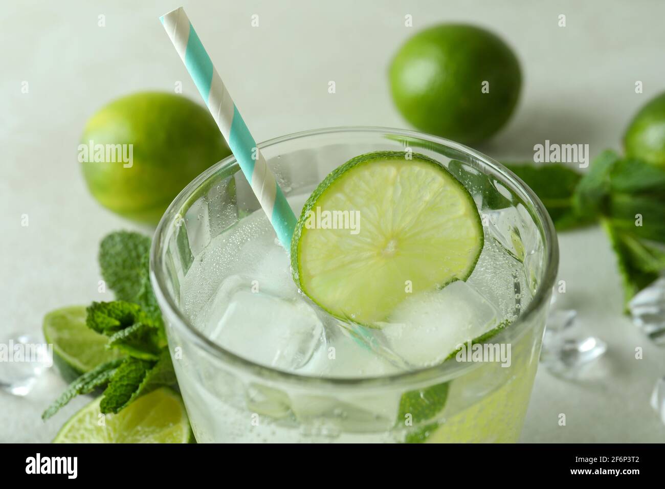 Glass of mojito cocktail and ingredients on white textured background ...