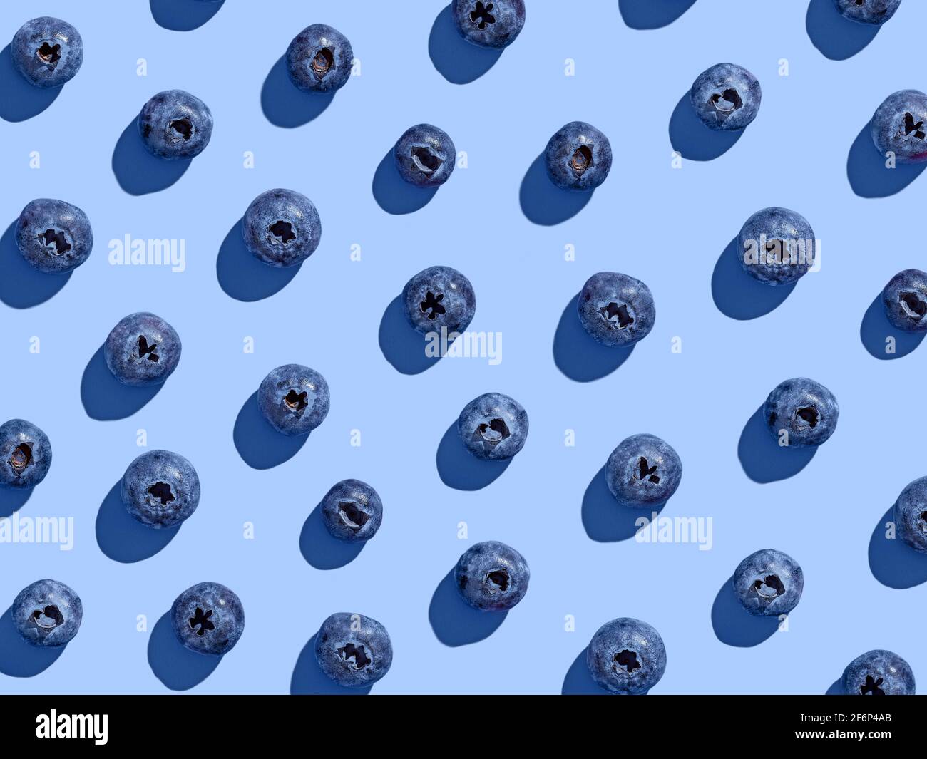 Colorful blueberry pattern on blue background, from above, hard shadow ...