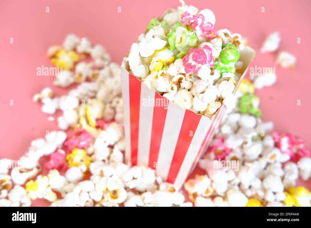 popcorn spilling from a container on red background Stock Photo - Alamy