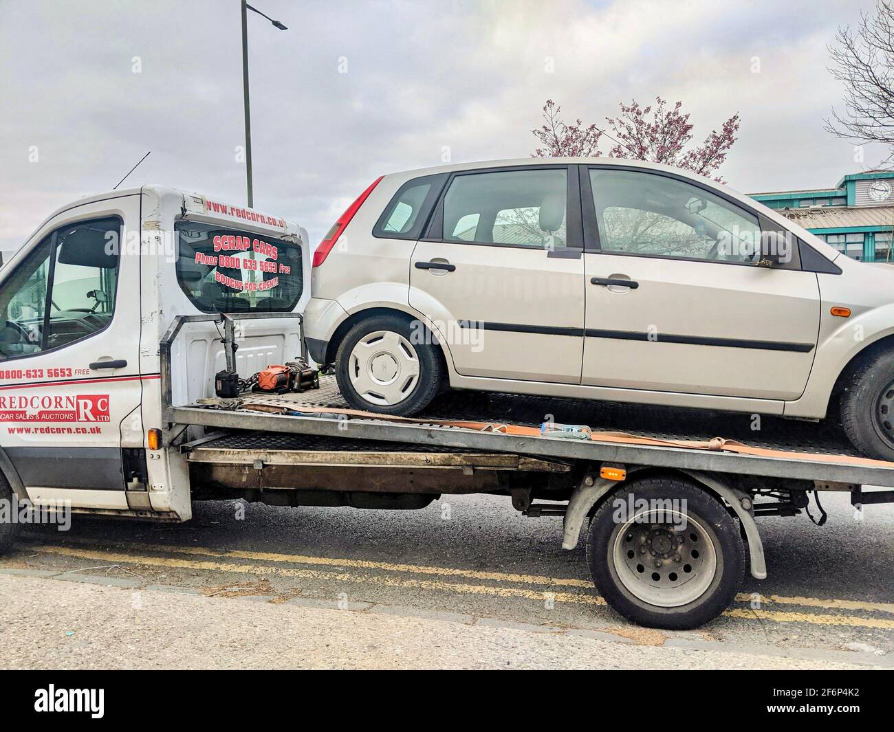 An old, broken down, silver Ford Fiesta being secured to a removal ...