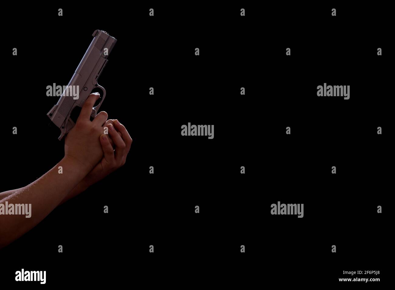 Child's hands holding a gun isolated on black background with copy ...