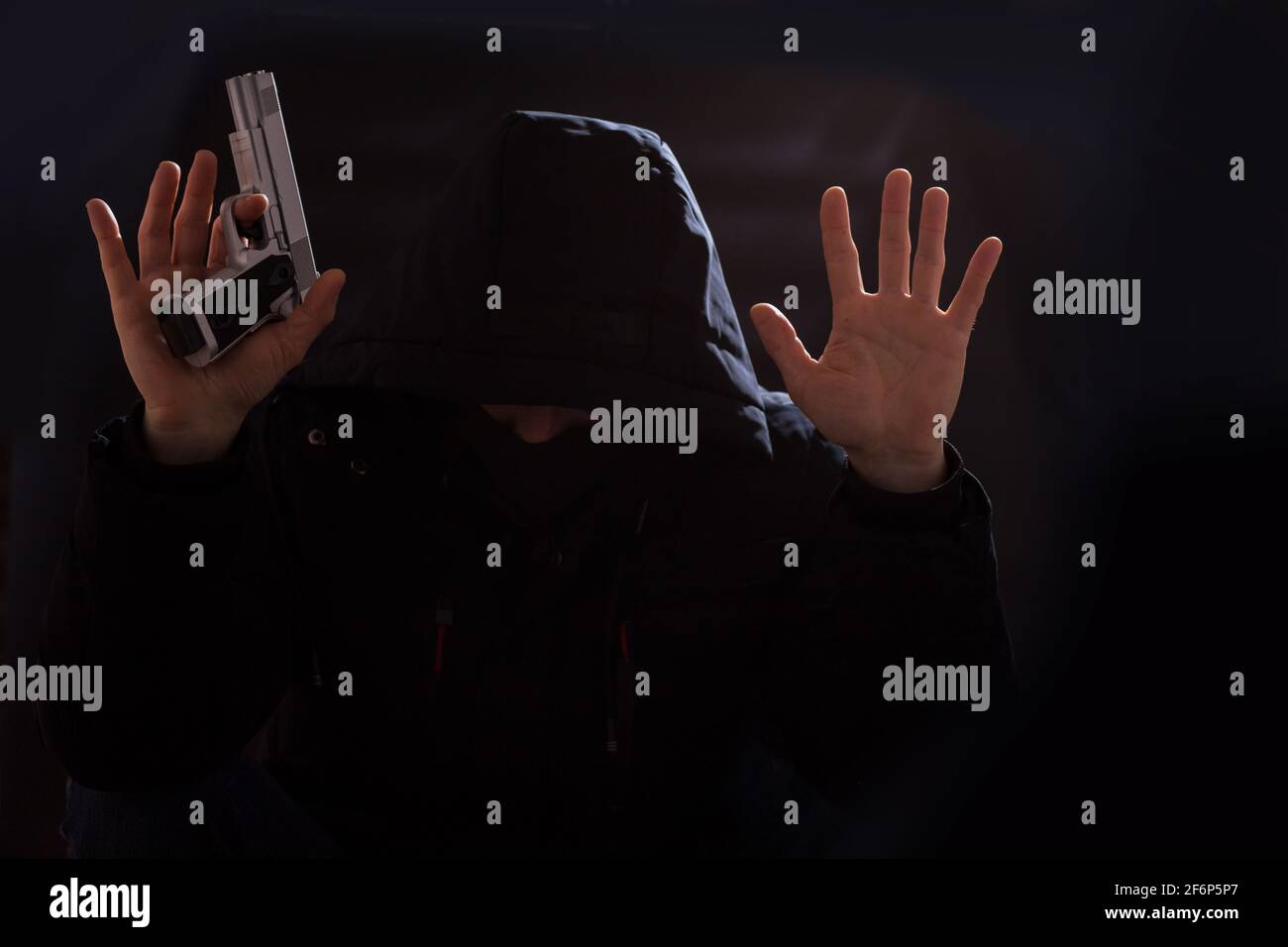The man with the gun raised his hands up, on black background Stock ...