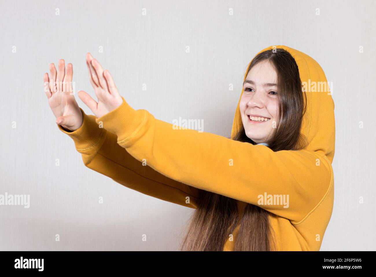 The teenage girl stretches her arms forward, shows to the side, warms ...