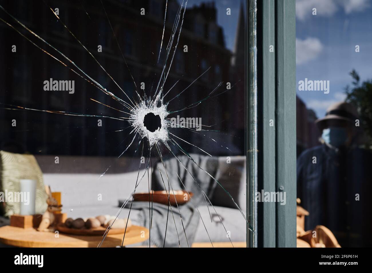 Broken shop window pane that looks like a bullet hole with sunlight ...