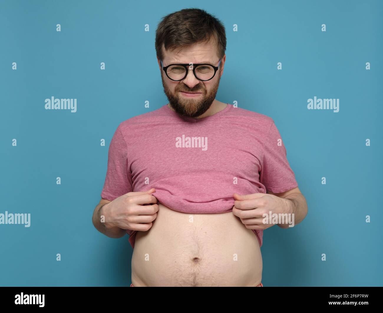 Disgruntled obese man shows off his excess belly fat and stares in ...