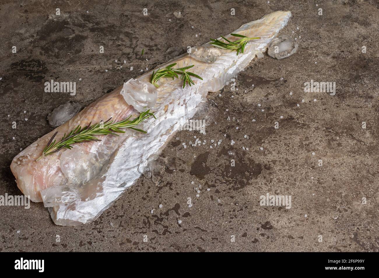 Raw frozen hake fillet with ice and fresh rosemary. Healthy food ...